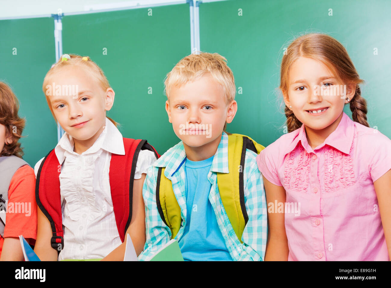 Three kids stand together in front of blackboard Stock Photo - Alamy
