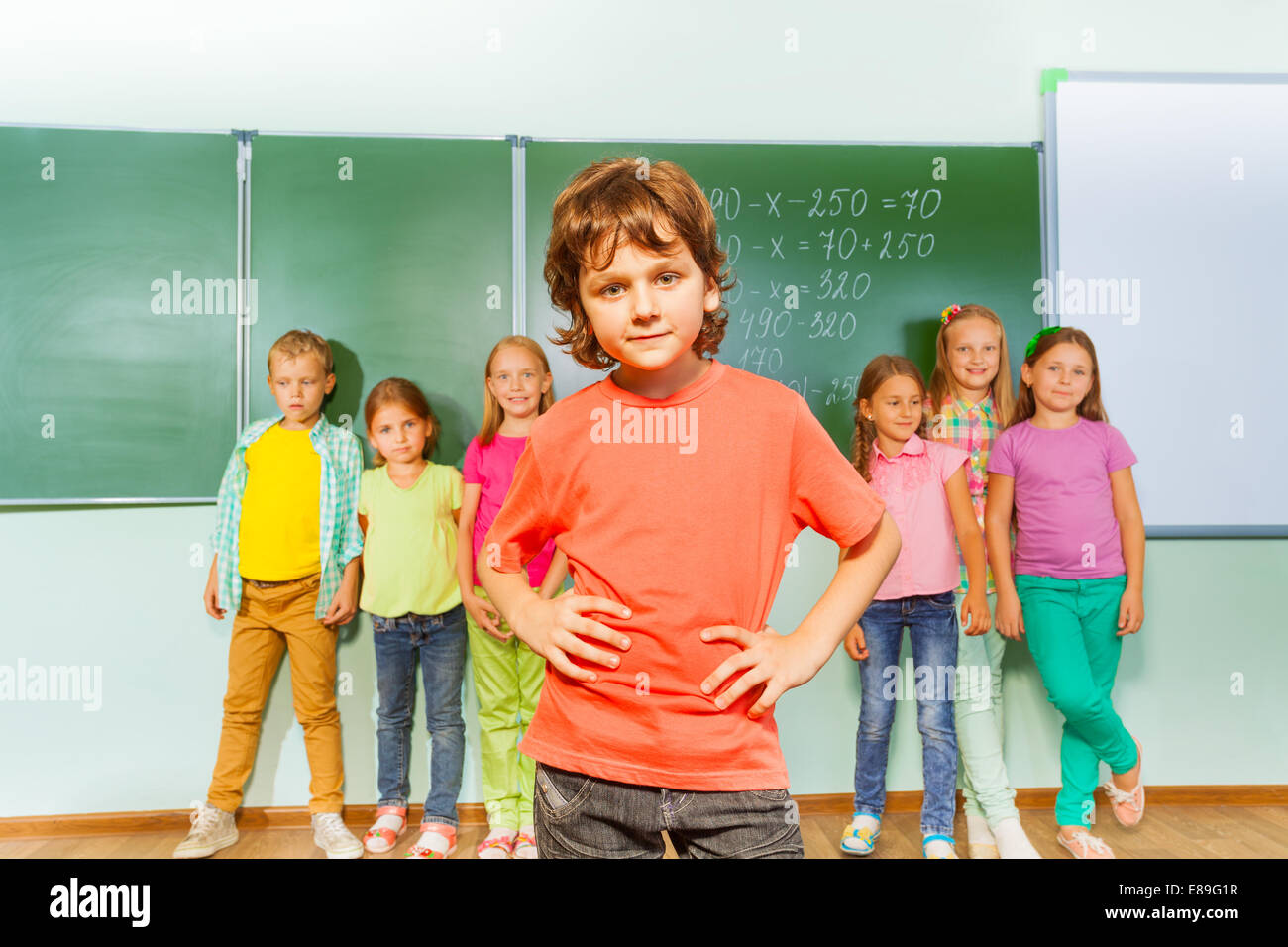 Boy stands in front of kids near blackboard Stock Photo - Alamy