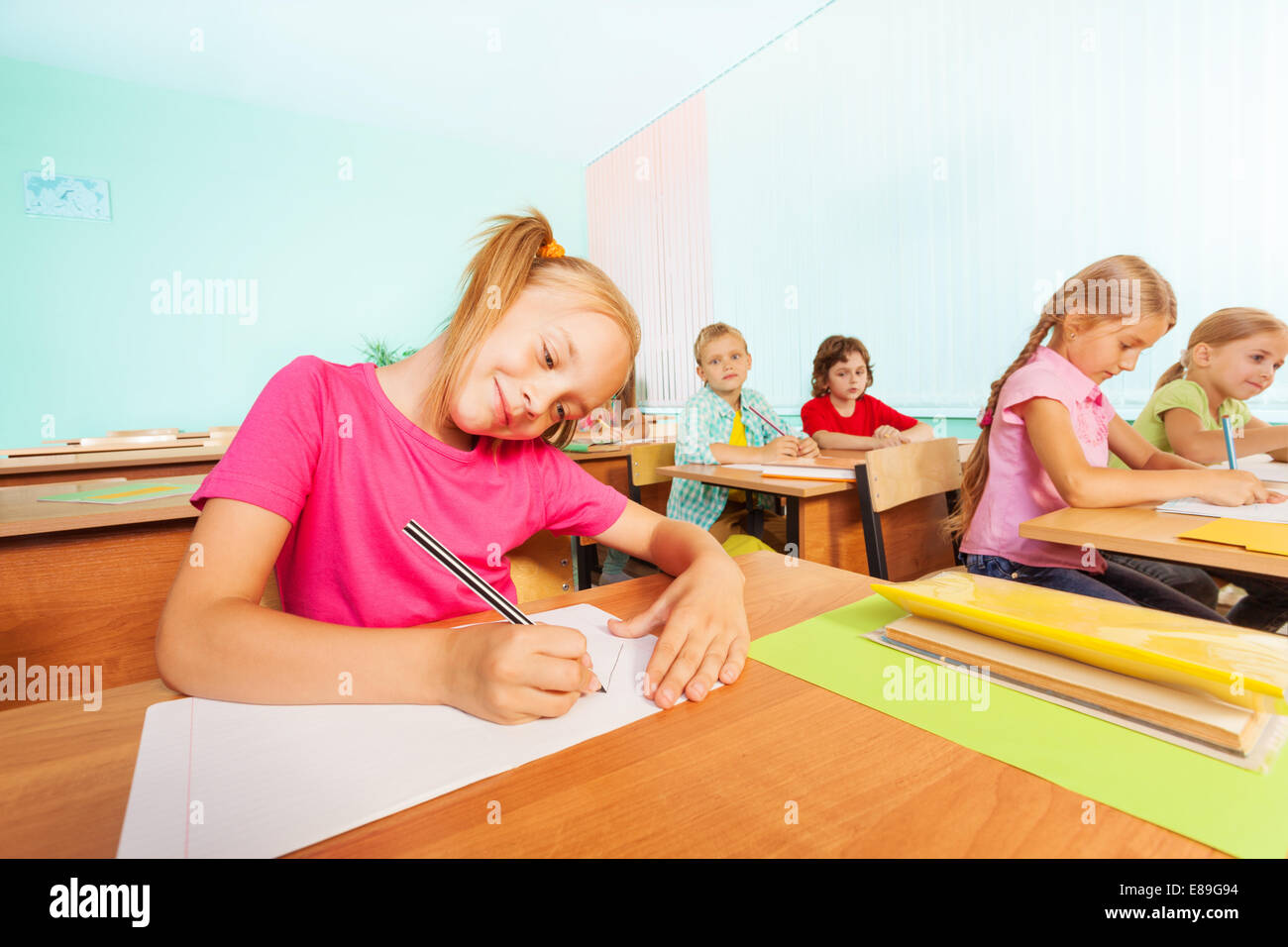 Smiling kids writing in classroom during lesson Stock Photo - Alamy