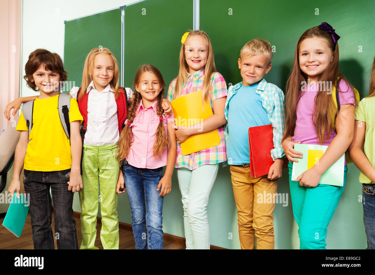 Happy children stand with text books in row Stock Photo - Alamy