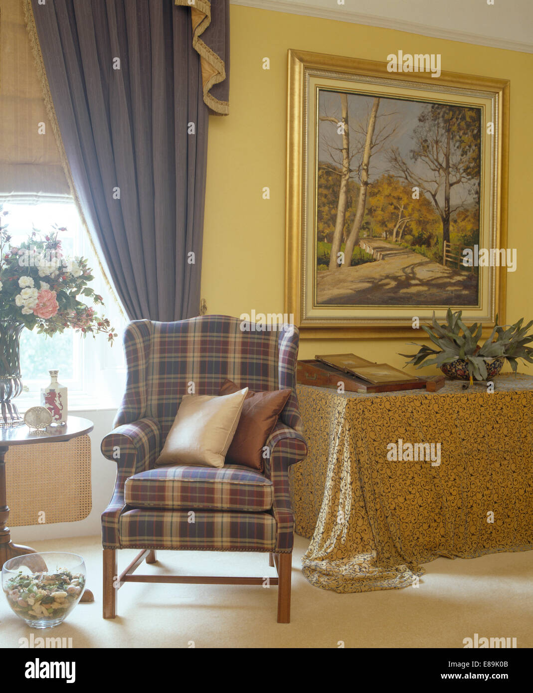 Checked armchair beside window with blue drapes in living room with ...