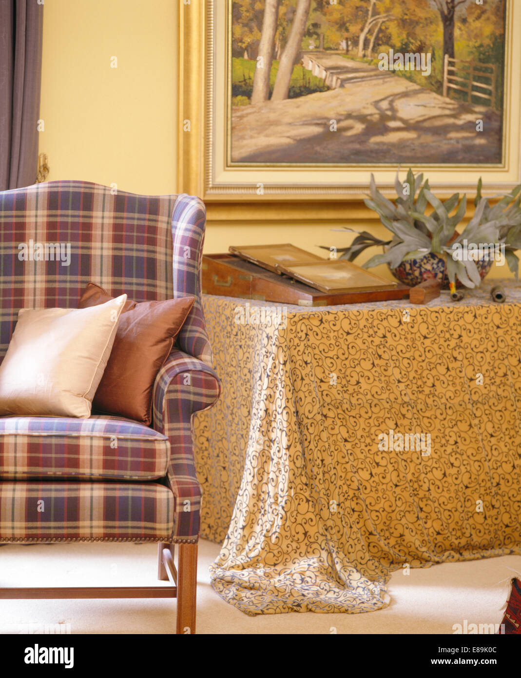 Checked armchair beside table with patterned yellow cloth Stock Photo ...