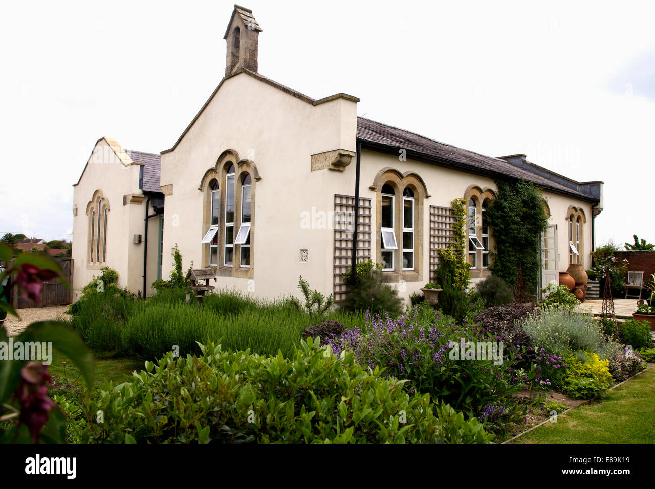 White painted converted country school with green shrubs growing in ...