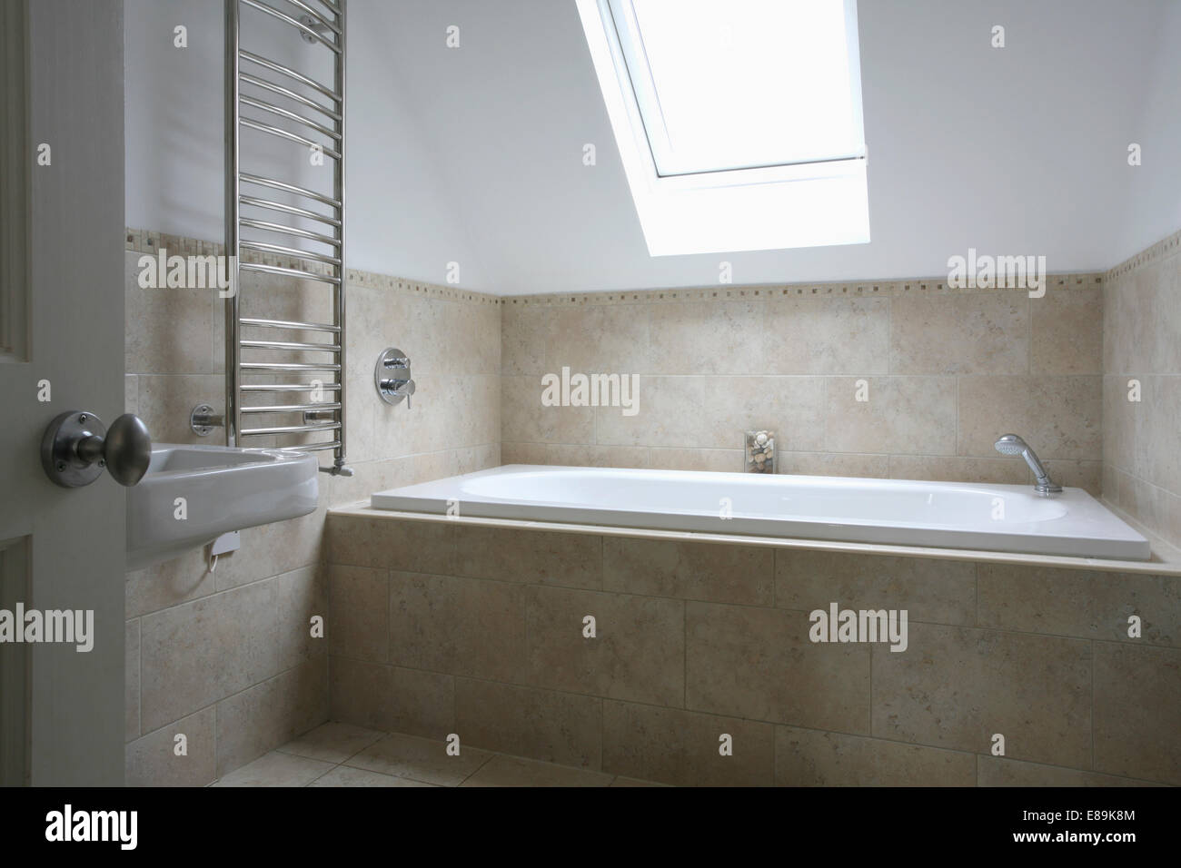 Velux window and limestone wall tiles above bath in modern attic ...