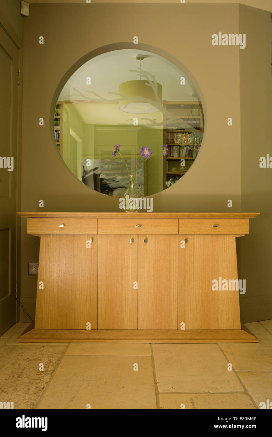Round mirror above modern wood sideboard Stock Photo - Alamy