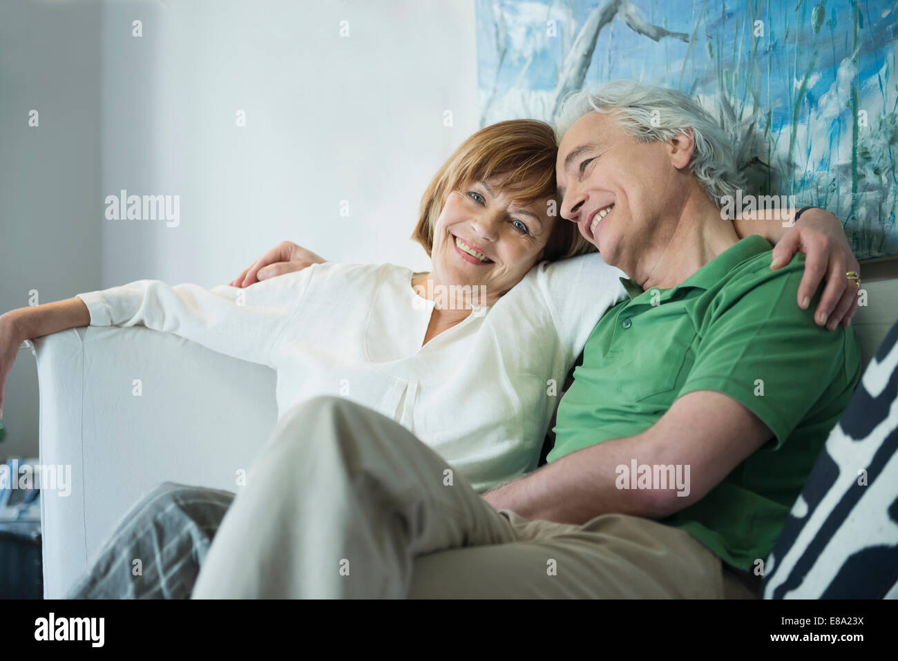 Couple relaxing on couch, smiling Stock Photo - Alamy