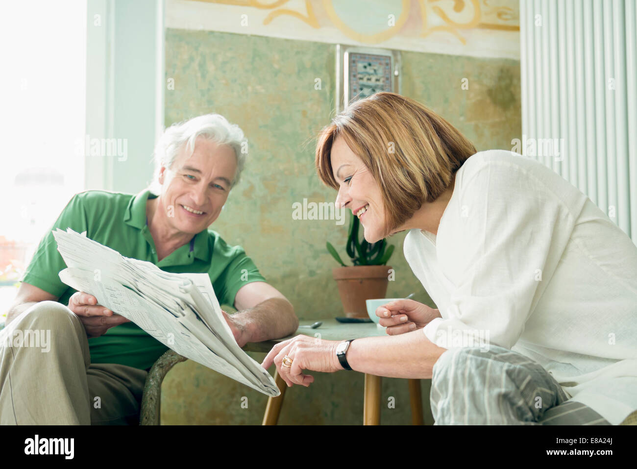 Couple reading newspaper together, smiling Stock Photo - Alamy