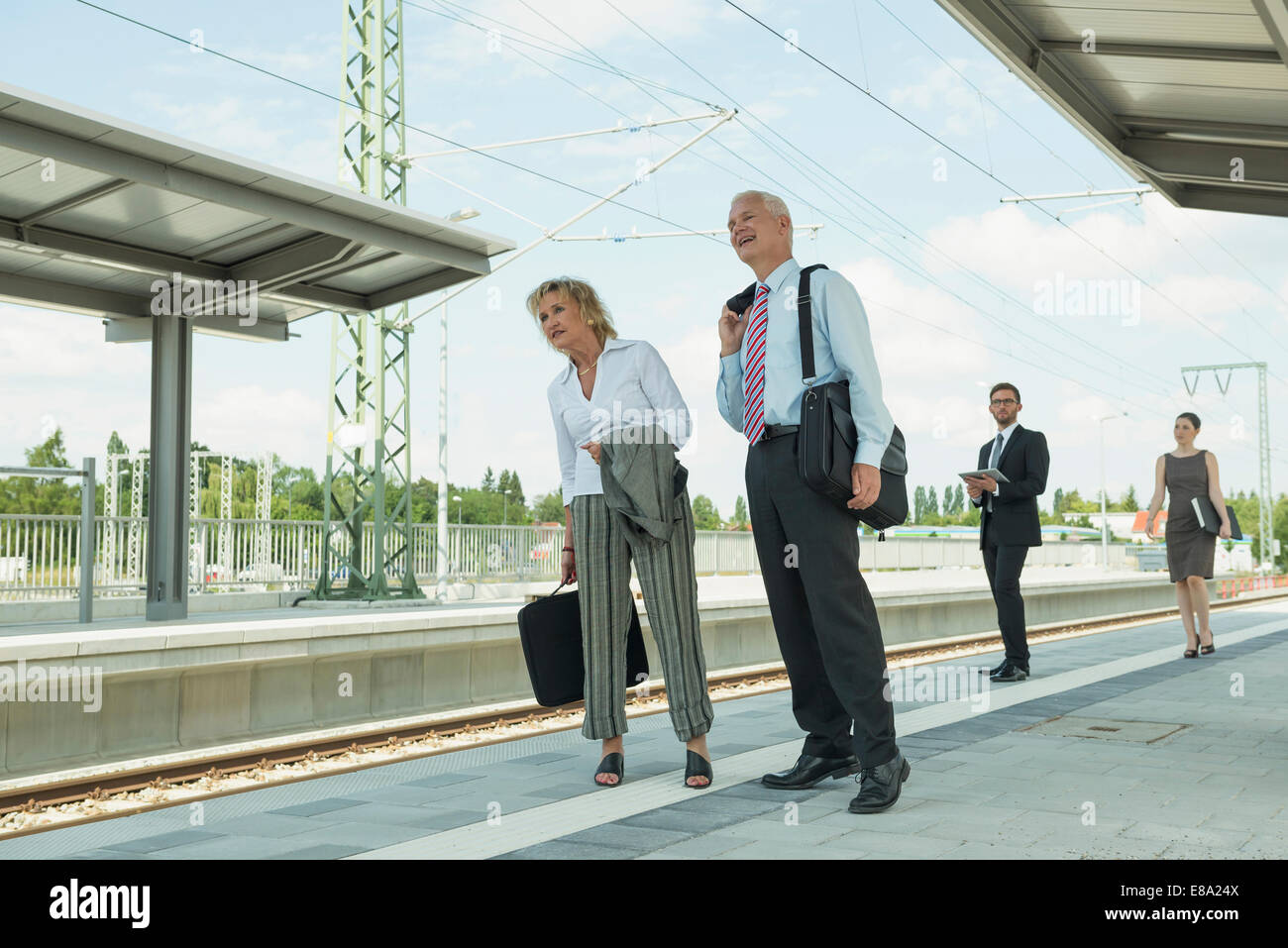 Four businessmen waiting for train Stock Photo - Alamy