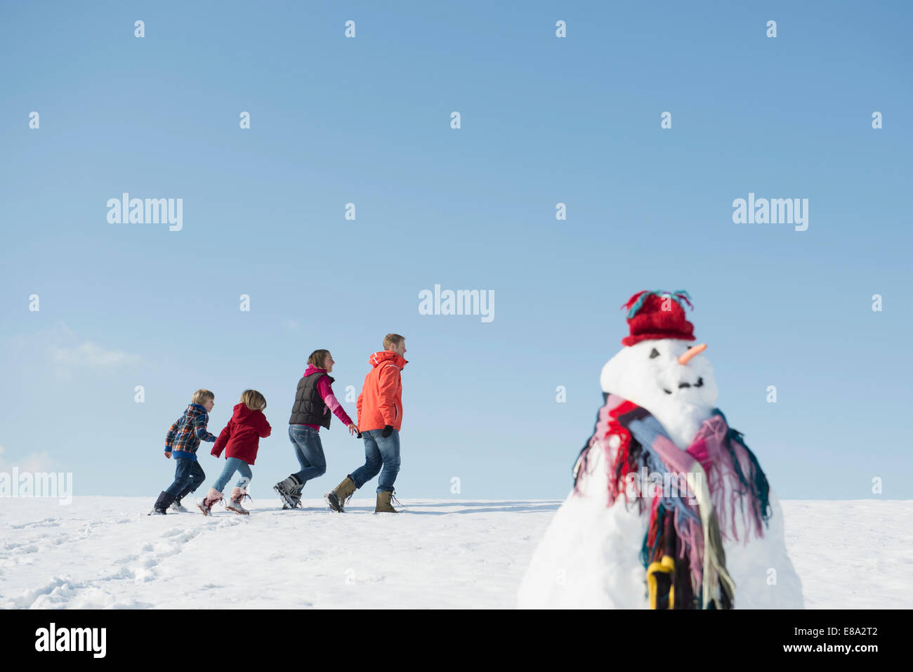 Family talking walk in winter, snowman in foreground, Bavaria, Germany ...