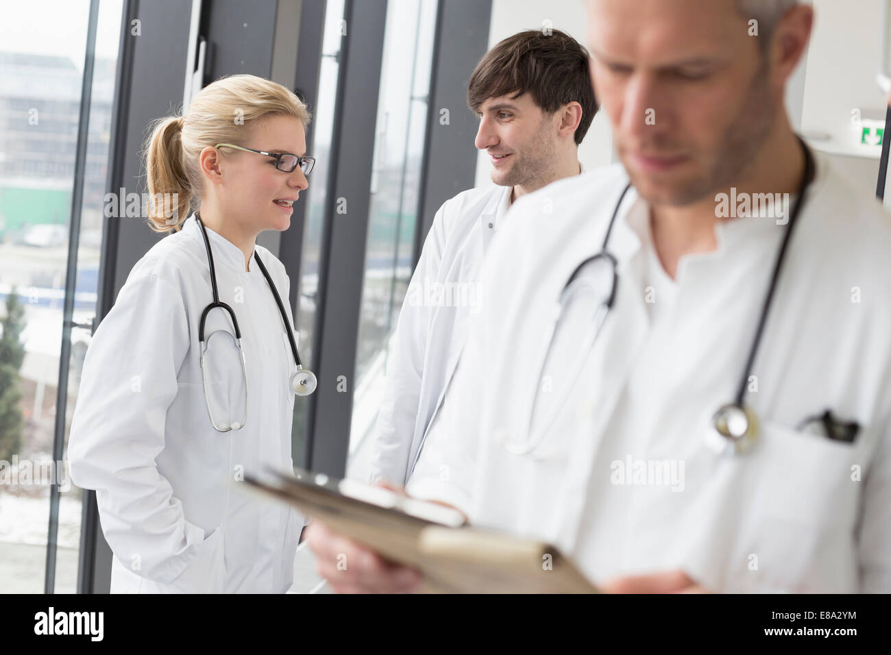Doctor reading file while colleagues in background Stock Photo - Alamy