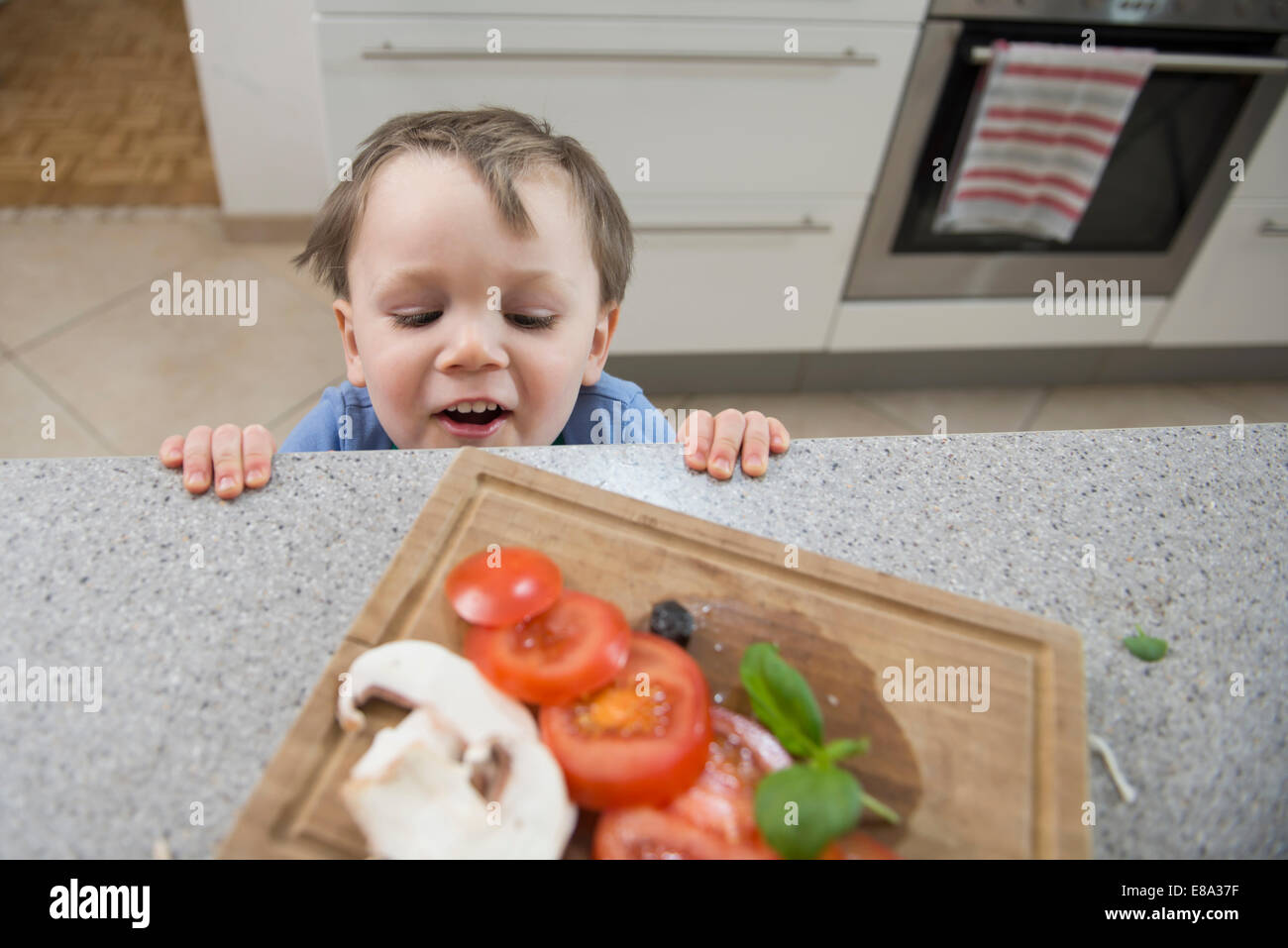 Boy looking at chopped vegetables in kitchen Stock Photo - Alamy