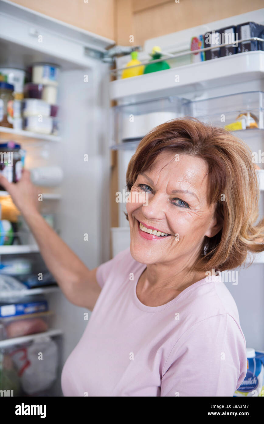 Portrait of senior woman infront of open refrigerator, smiling Stock ...
