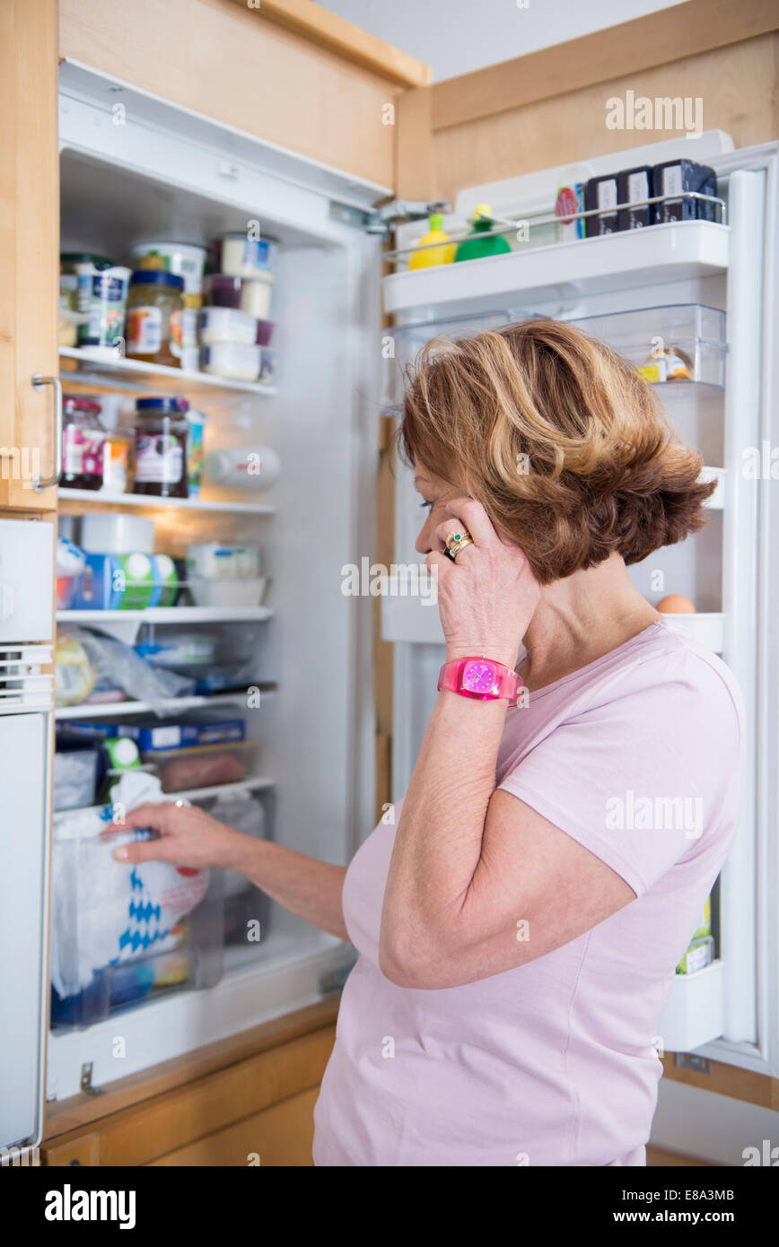 Senior woman infront of open refrigerator, smiling Stock Photo - Alamy