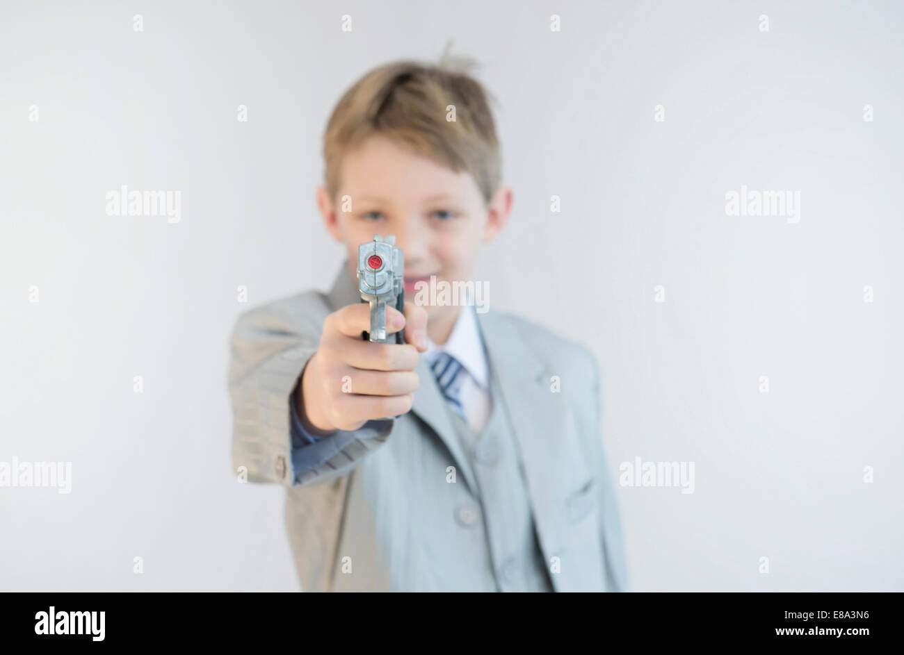 Boy holding toy gun and playing gangster, smiling, portrait Stock Photo ...