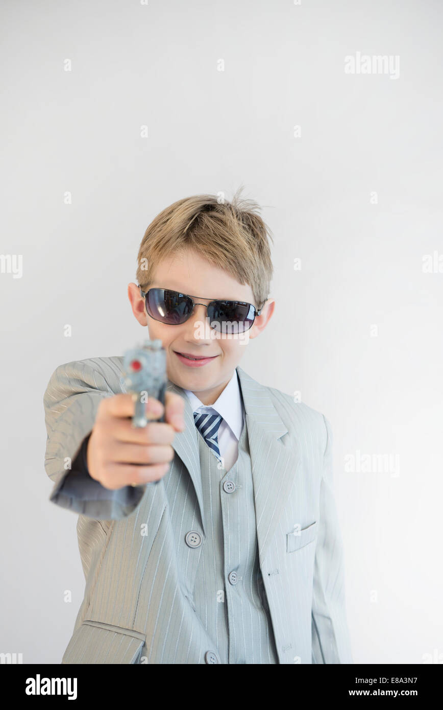 Boy holding toy gun and playing gangster, smiling Stock Photo - Alamy