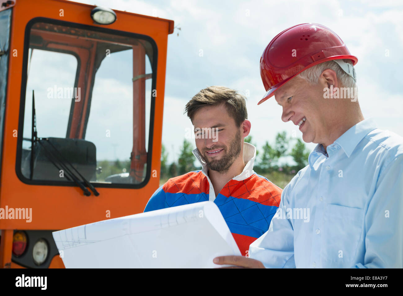 Building owner and construction worker discussing construction plan ...