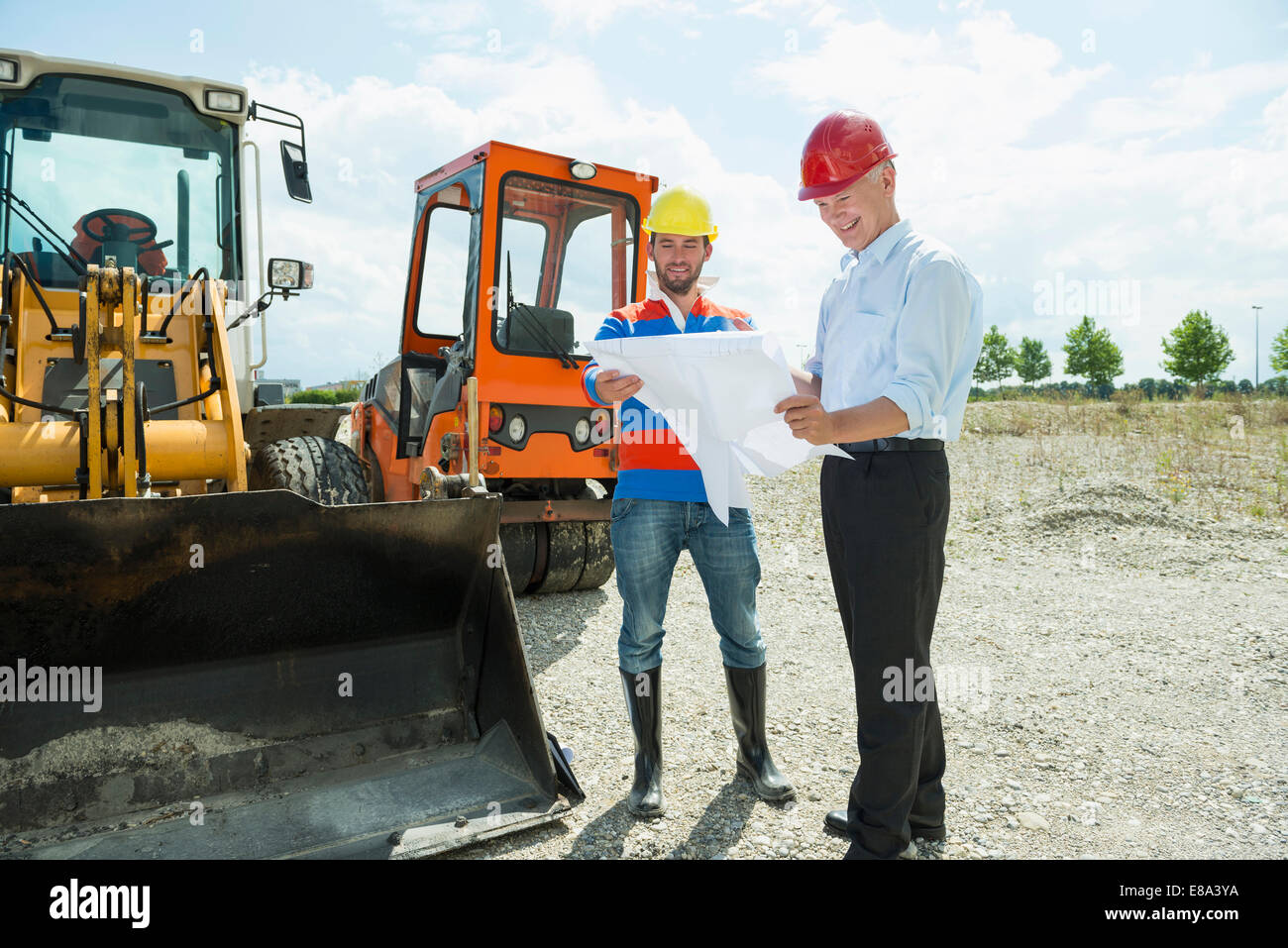 Building owner and construction worker discussing construction plan ...