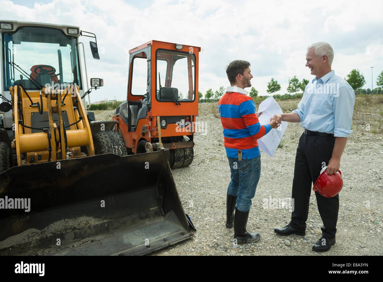 Building owner and construction worker discussing construction plan ...