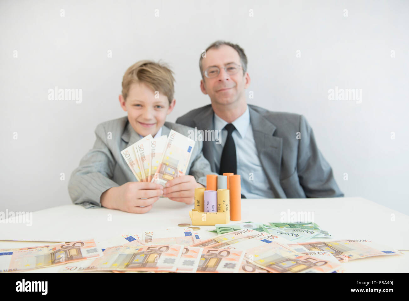 Father and son with Euro coin, paper money and coin rolls, smiling ...