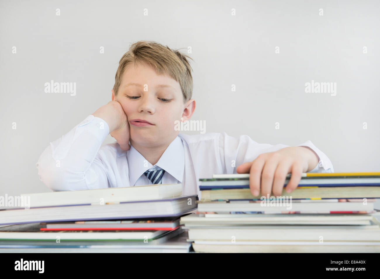 Frustrated boy with stack of books, close up Stock Photo - Alamy
