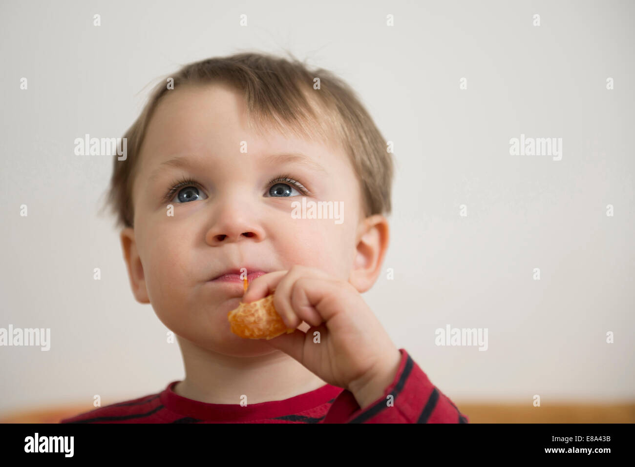 Boy eating mandarin Stock Photo - Alamy