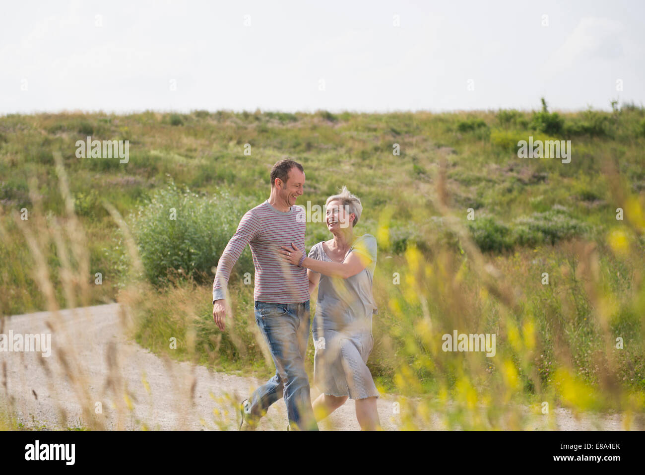 Mature couple running on field in summer, smiling Stock Photo - Alamy