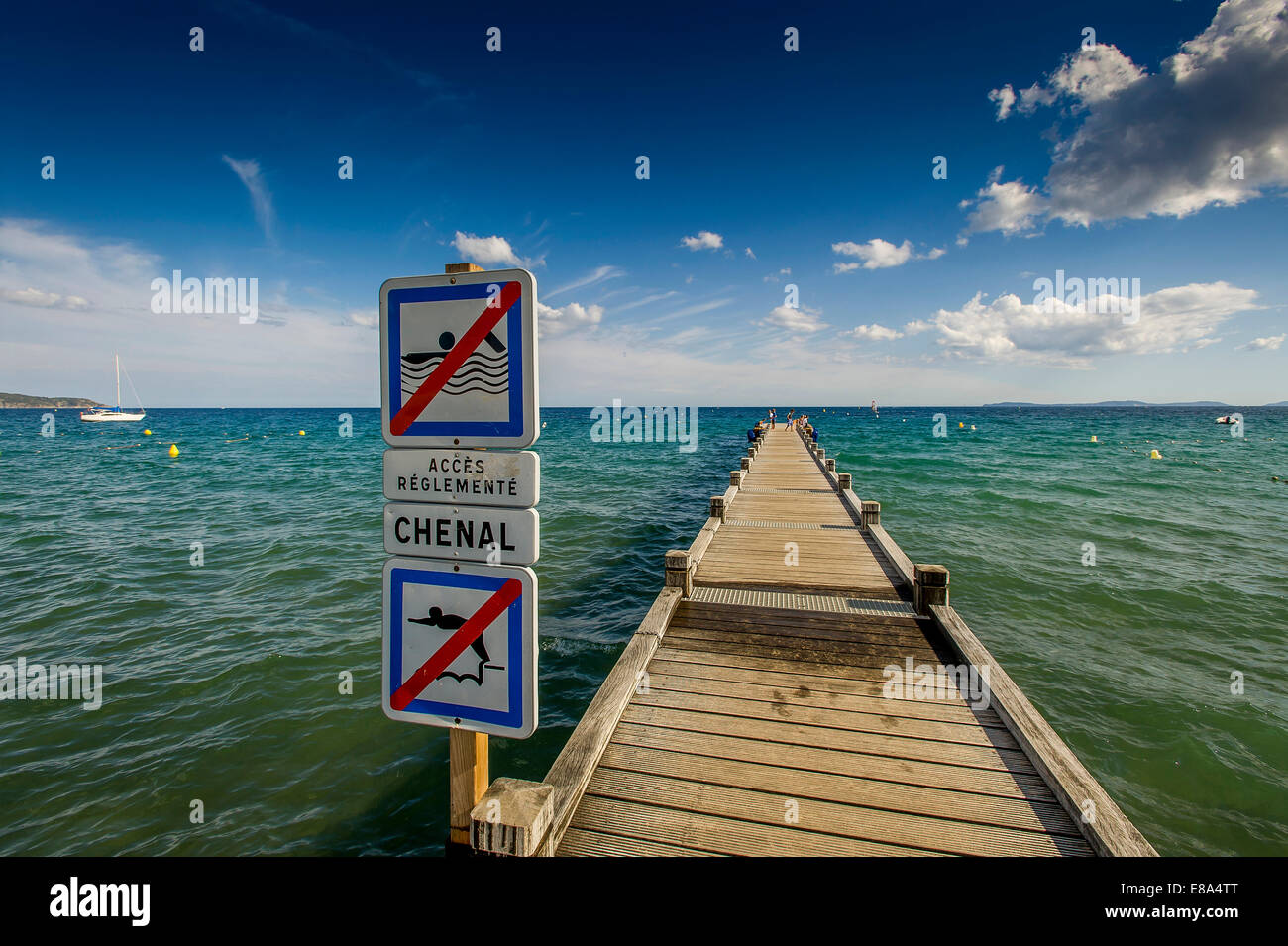 Wooden sea wharf with warning signs for swimmers and blue hi-res stock ...
