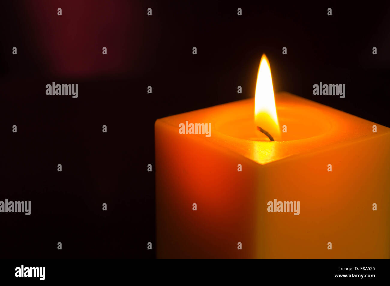 The yellow candle burning in the dark Stock Photo - Alamy