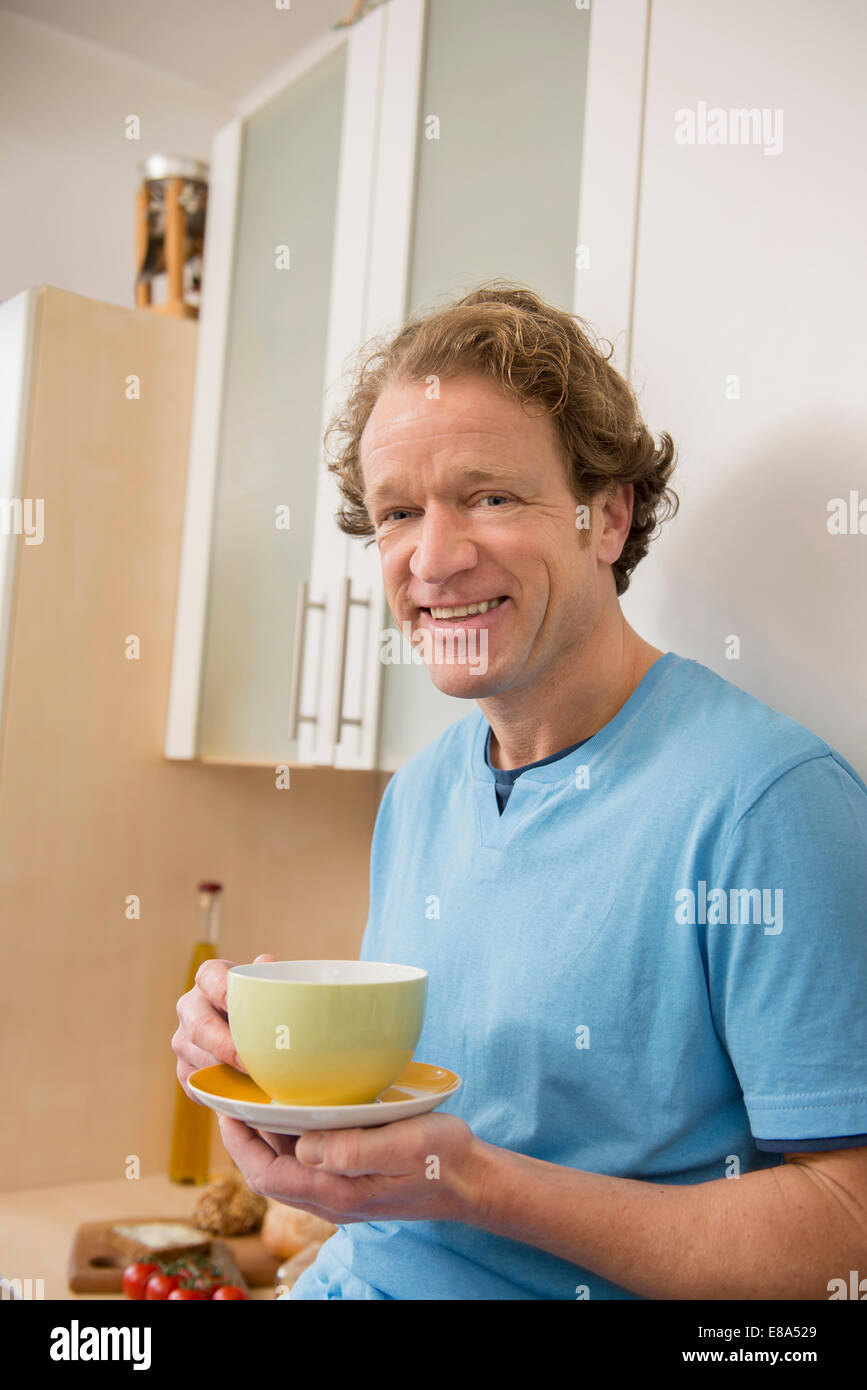 Smiling man with cup of coffee in kitchen Stock Photo - Alamy