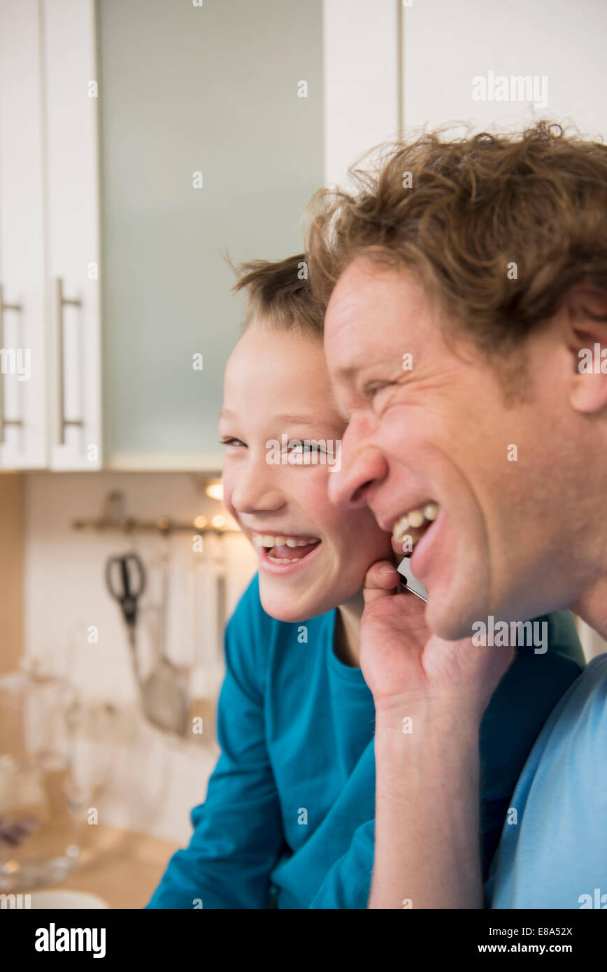 Laughing father and son with cell phone in kitchen Stock Photo - Alamy
