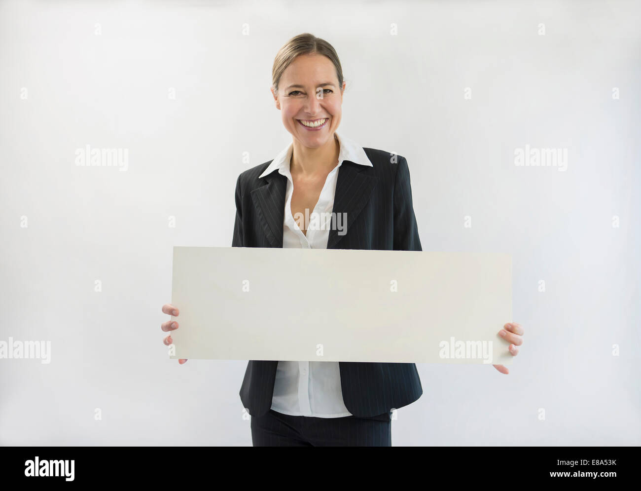 Portrait of businesswoman in black suit holding blank placard, smiling ...
