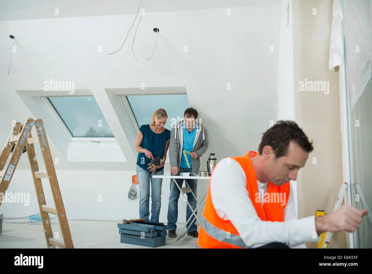Couple and construction worker at construction site of new building ...