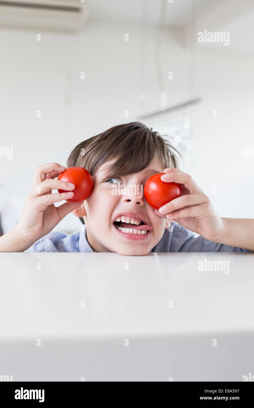 Boy making faces with tomatoes Stock Photo - Alamy