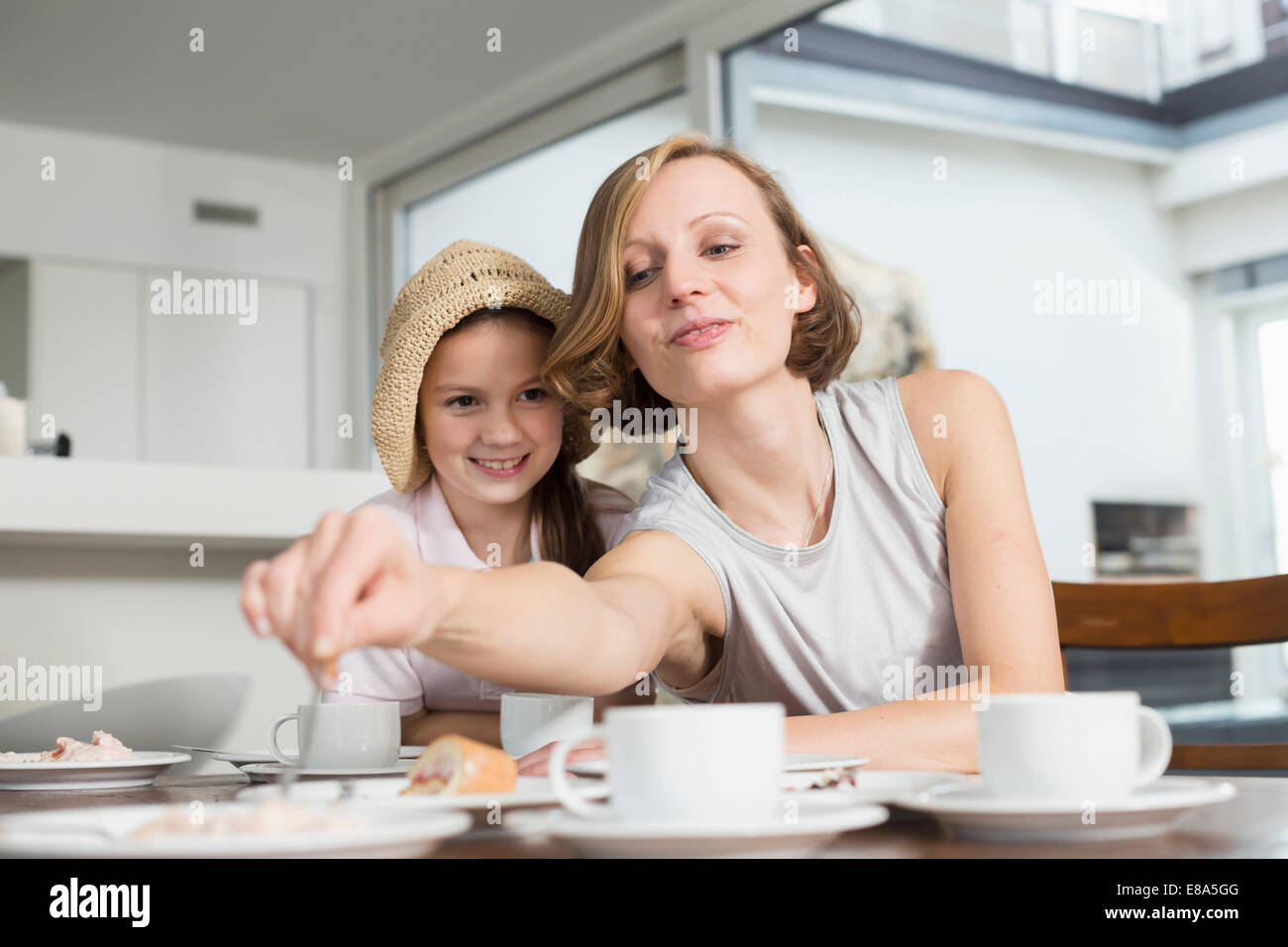 Mother and daughter at table eating cake Stock Photo - Alamy