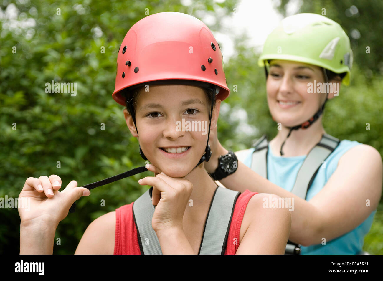 Young woman adjusting helmet of girl, smiling Stock Photo - Alamy