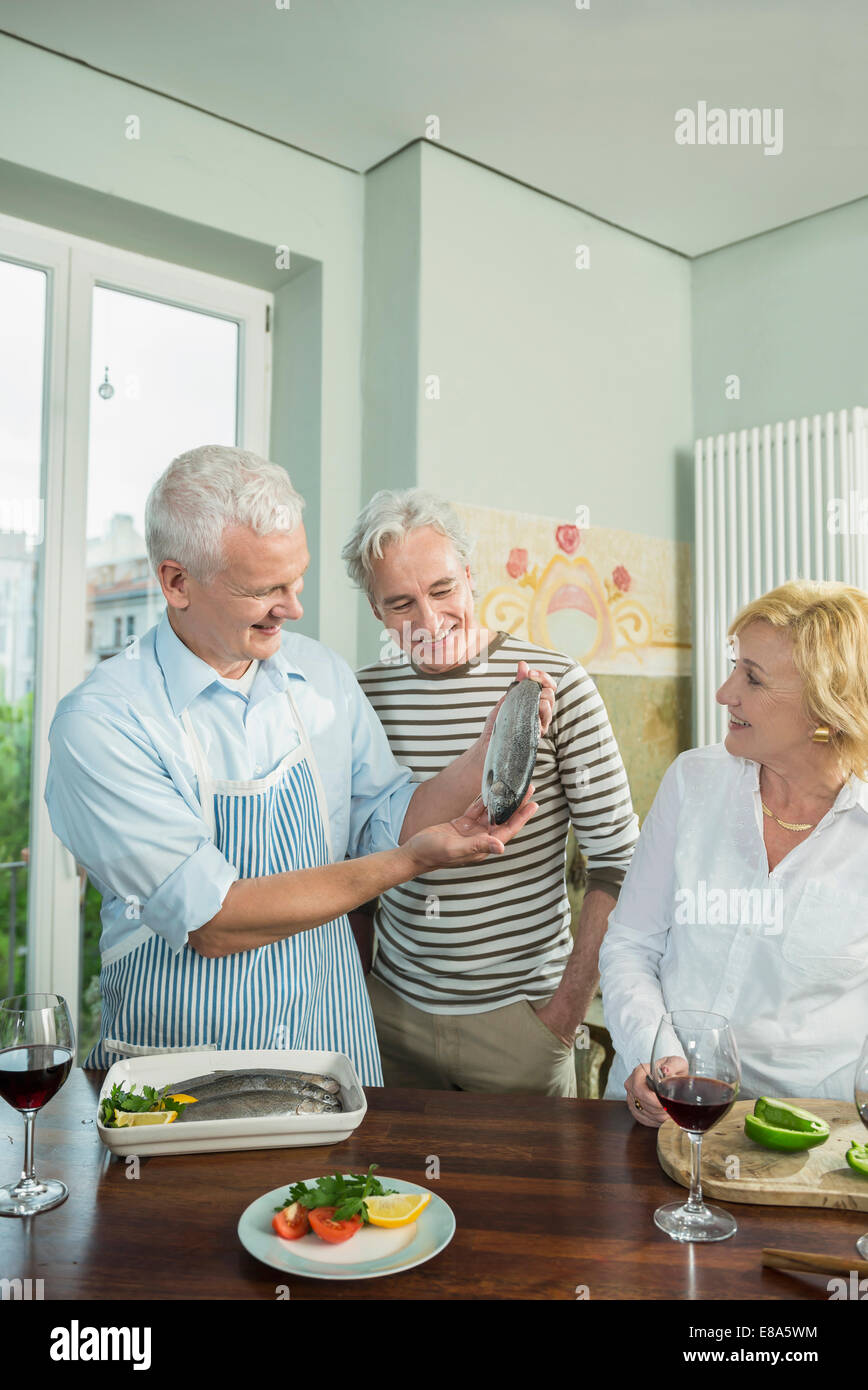 Friends presenting trout fish, smiling Stock Photo - Alamy