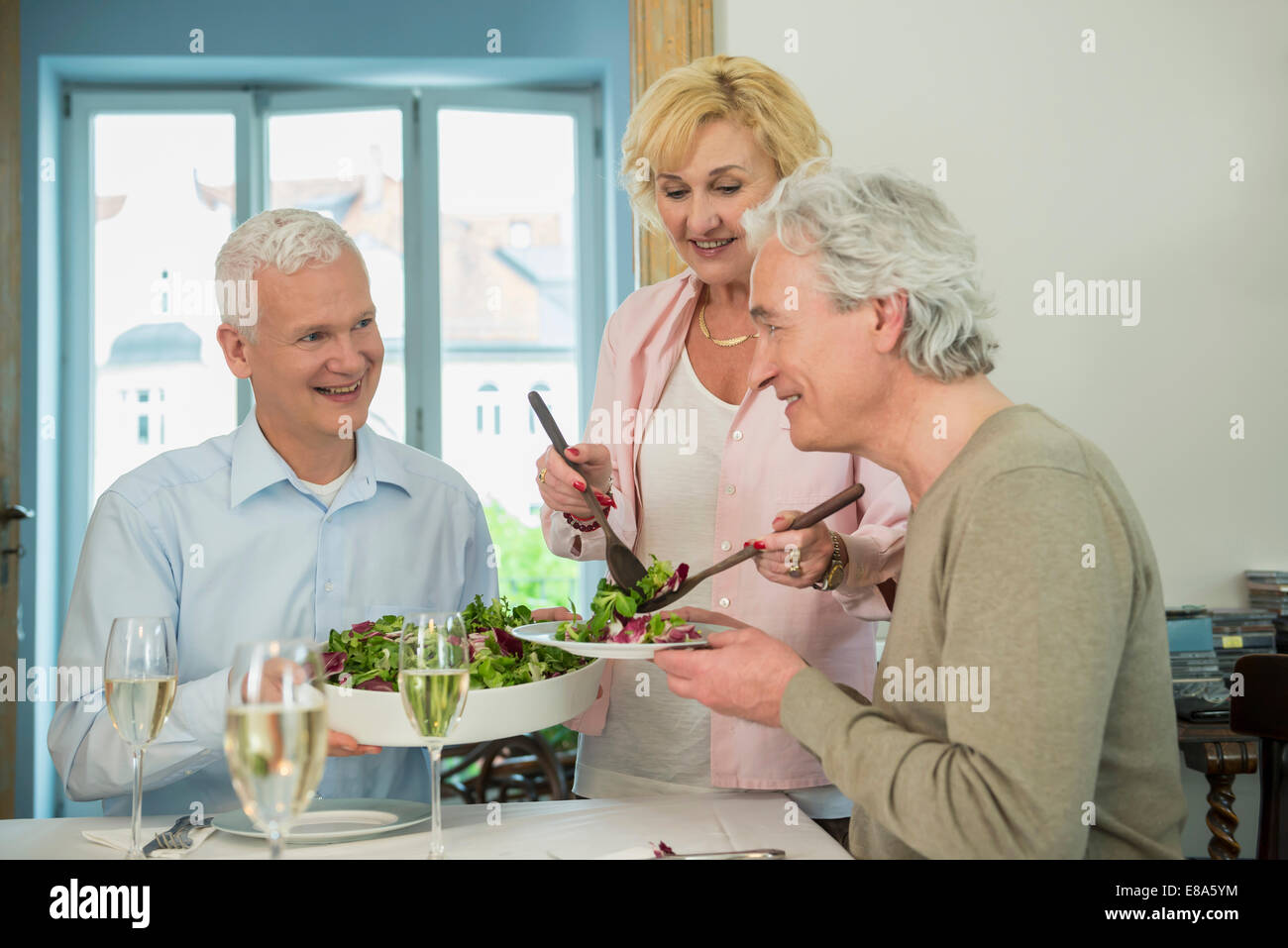 Woman serving salad to her friends, smiling Stock Photo - Alamy