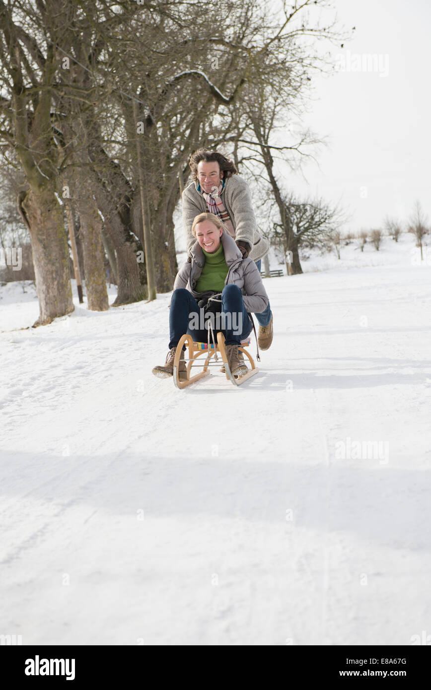 Man pushing woman on sledge in snow, Bavaria, Germany Stock Photo - Alamy