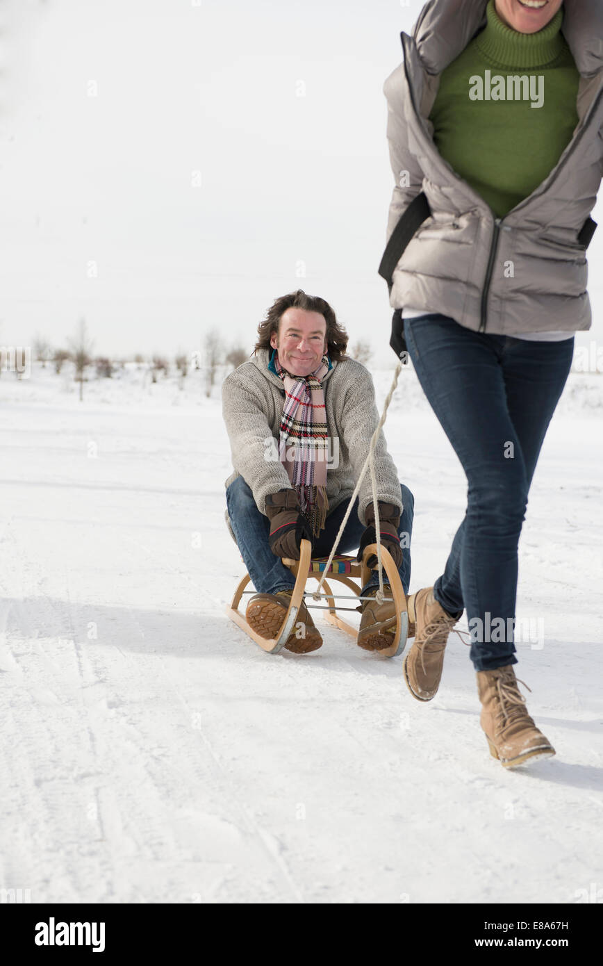 Woman dragging man on sledge in snow, Bavaria, Germany Stock Photo - Alamy