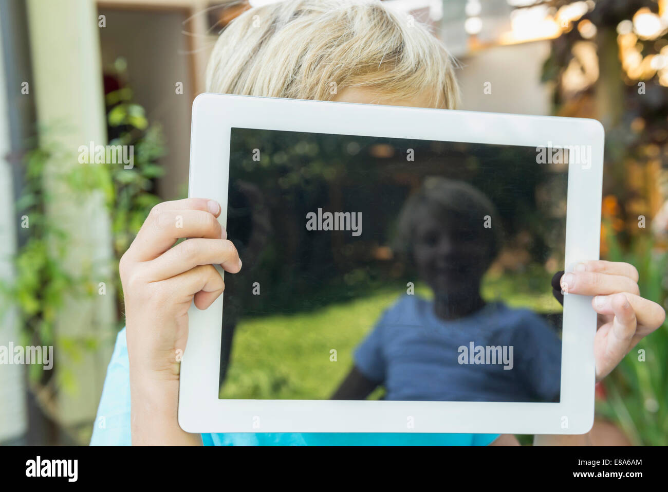Young boy hiding his face behind tablet computer Stock Photo - Alamy