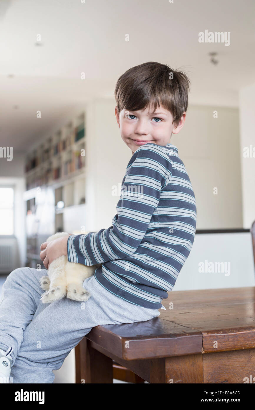 Portrait of boy sitting on table, smiling Stock Photo - Alamy