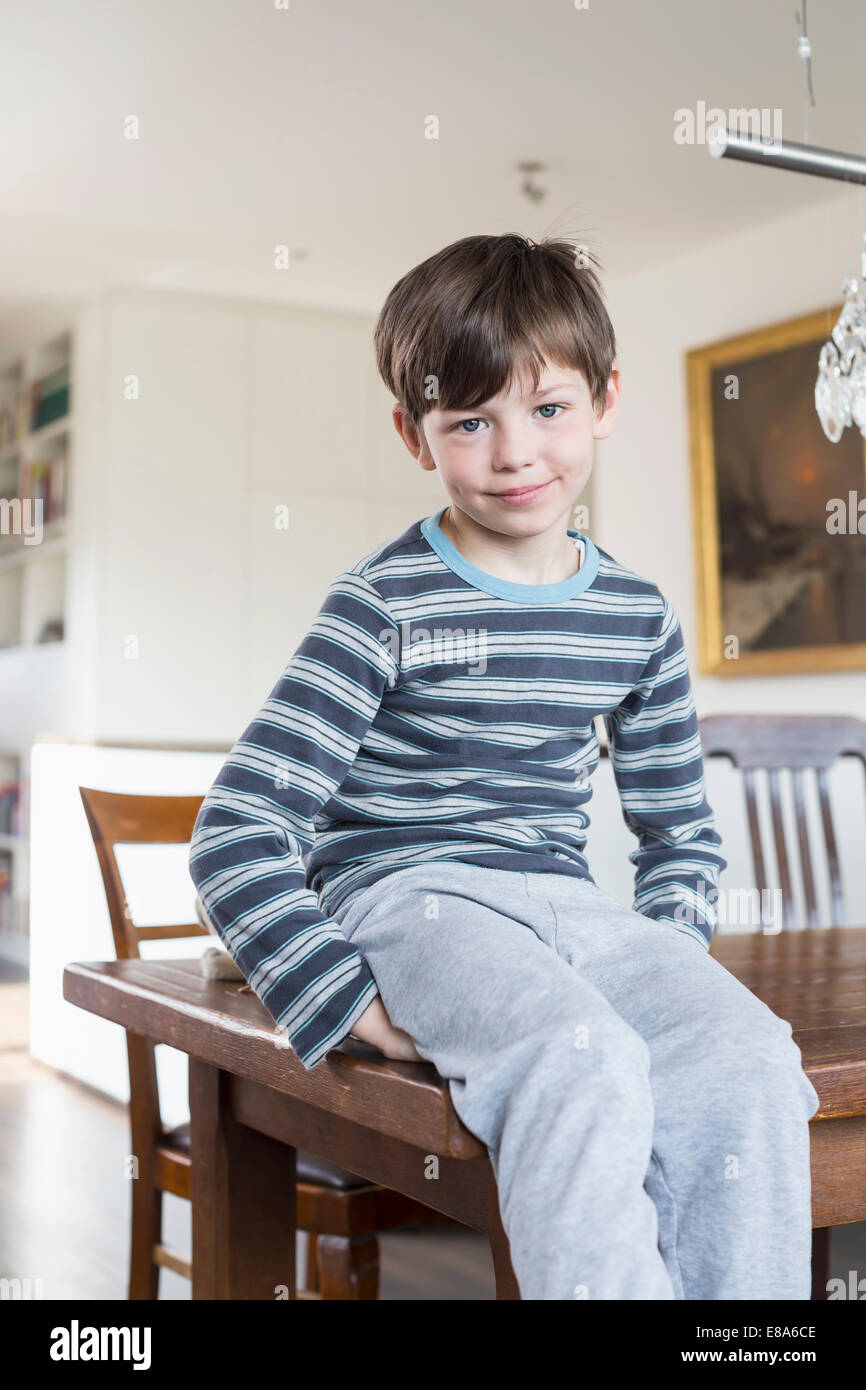 Portrait of boy sitting on table, smiling Stock Photo - Alamy