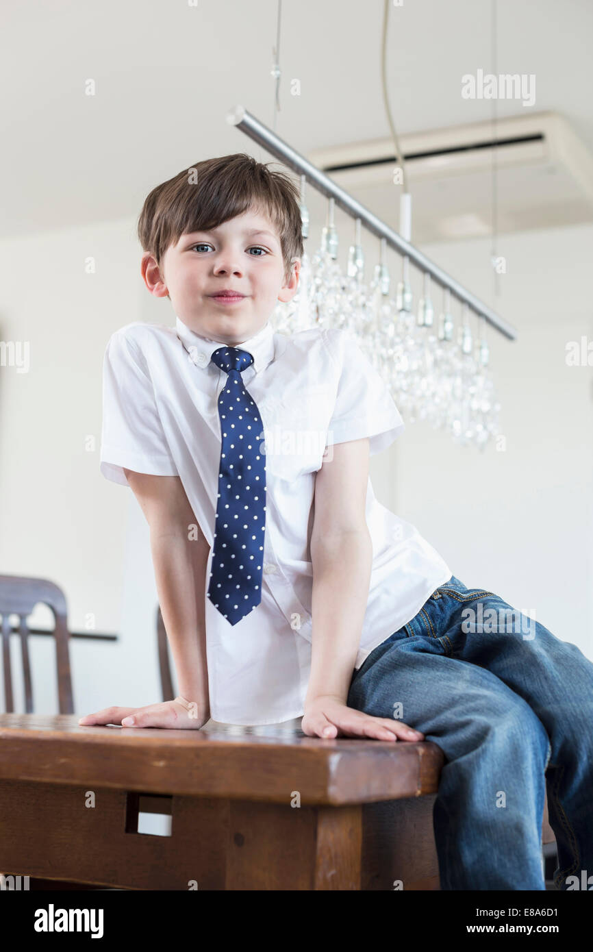 Portrait of boy sitting on table Stock Photo - Alamy