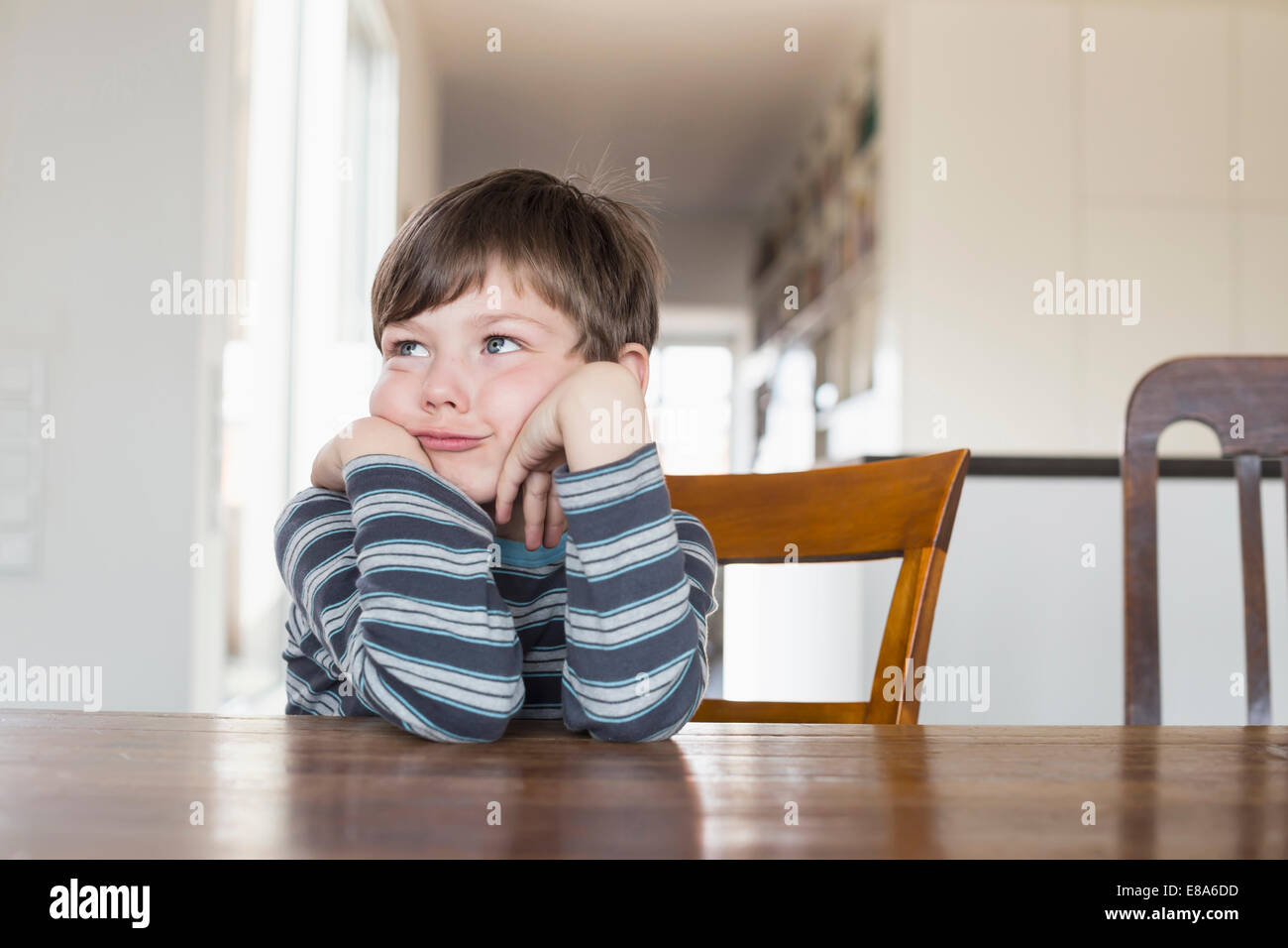 Boy leaning on wooden table, looking away Stock Photo - Alamy
