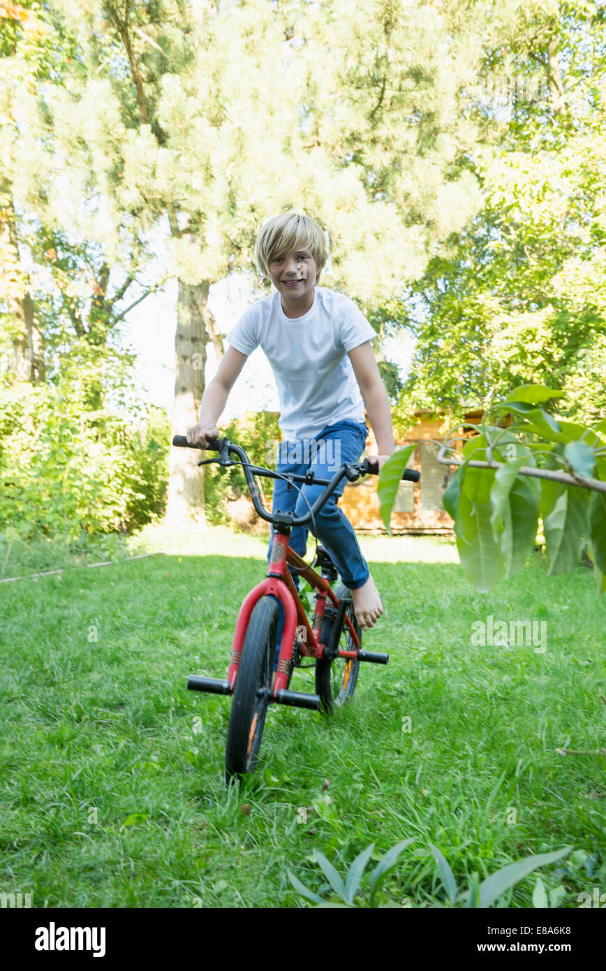 Young boy cycling in the garden Stock Photo - Alamy