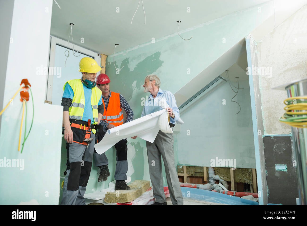 Architect and two construction workers at construction site of new ...