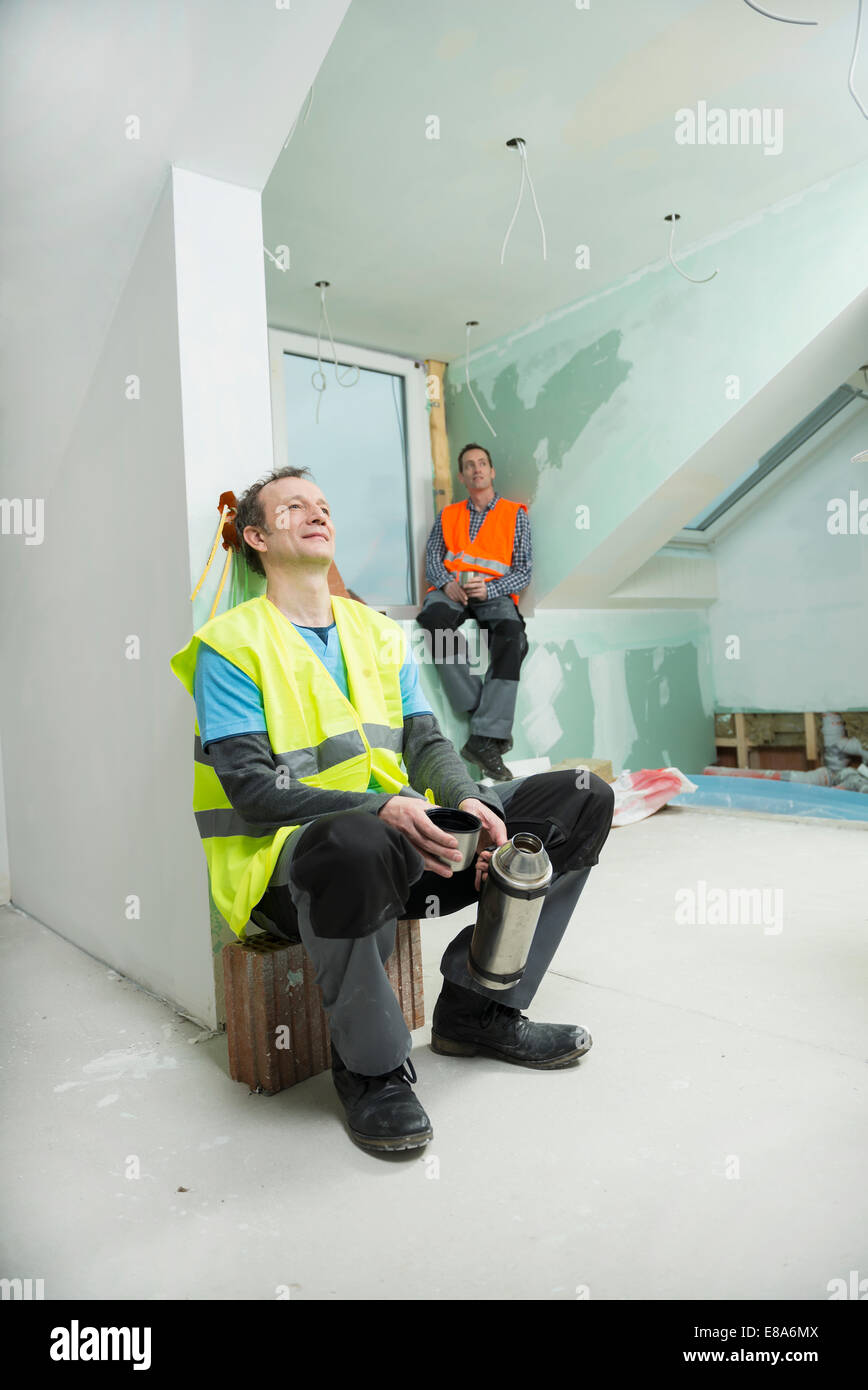 Two construction workers at construction site of new building having a ...