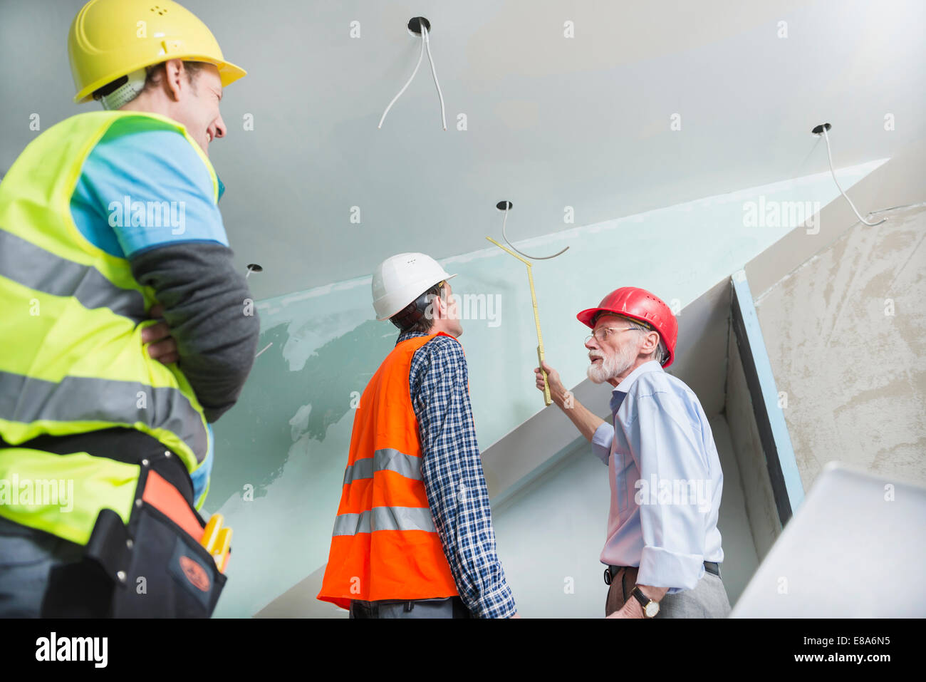 Architect and two construction workers at construction site of new ...