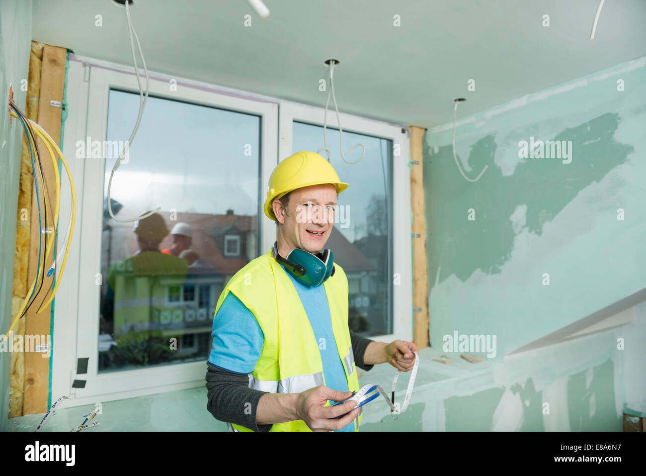 Portrait of construction worker with safety helmet and ear defenders ...