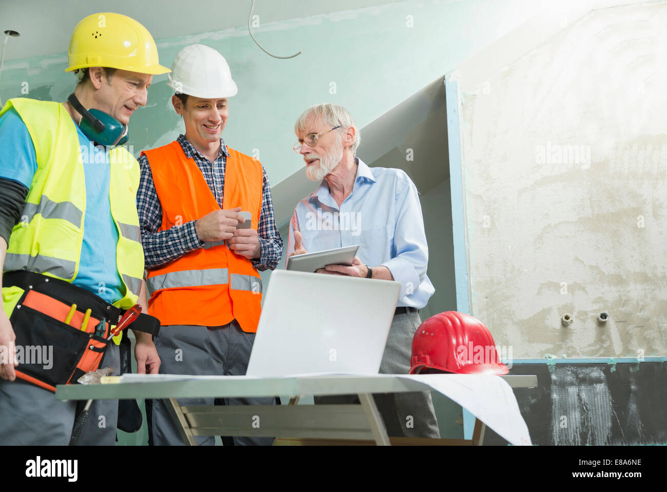 Architect and two construction workers at construction site of new ...